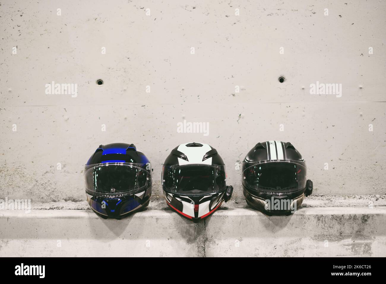 Three motorcycle helmets on a concrete background Stock Photo - Alamy