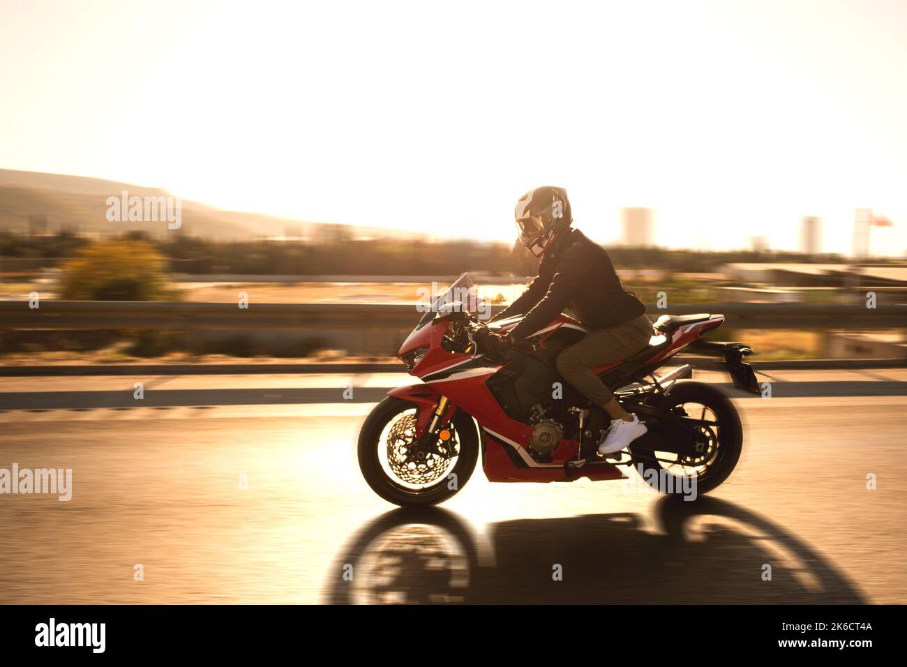 Side view of a biker riding red race motorcycle on the highway with ...