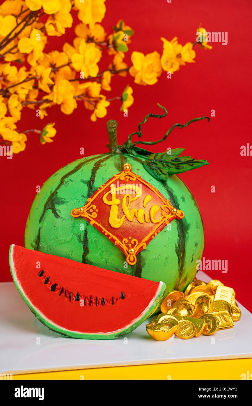 A watermelon-shaped cake with golden coins next to it and a red ...