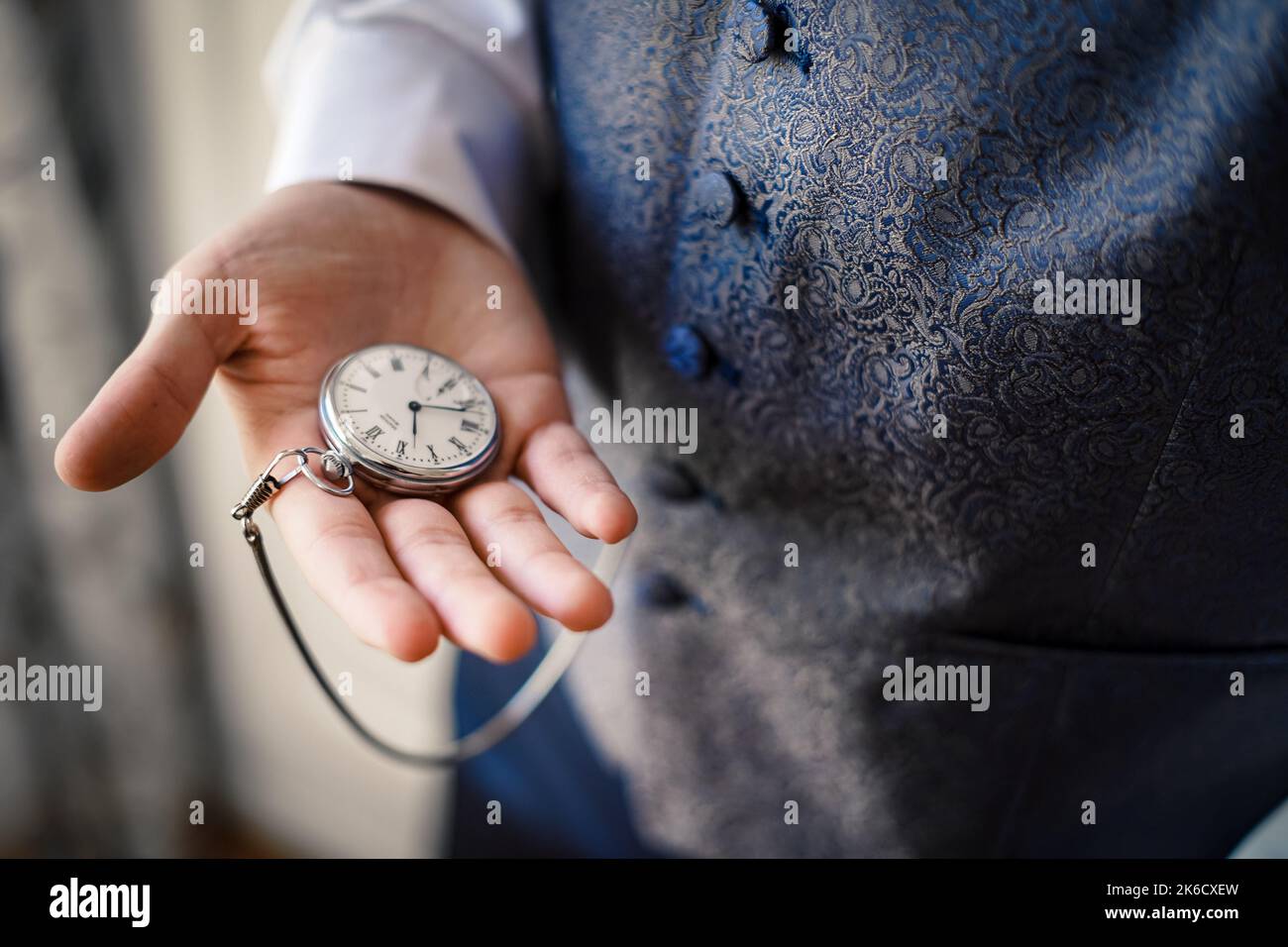 The hands of a man in an elegant suit holding a vintage stye fob watch ...