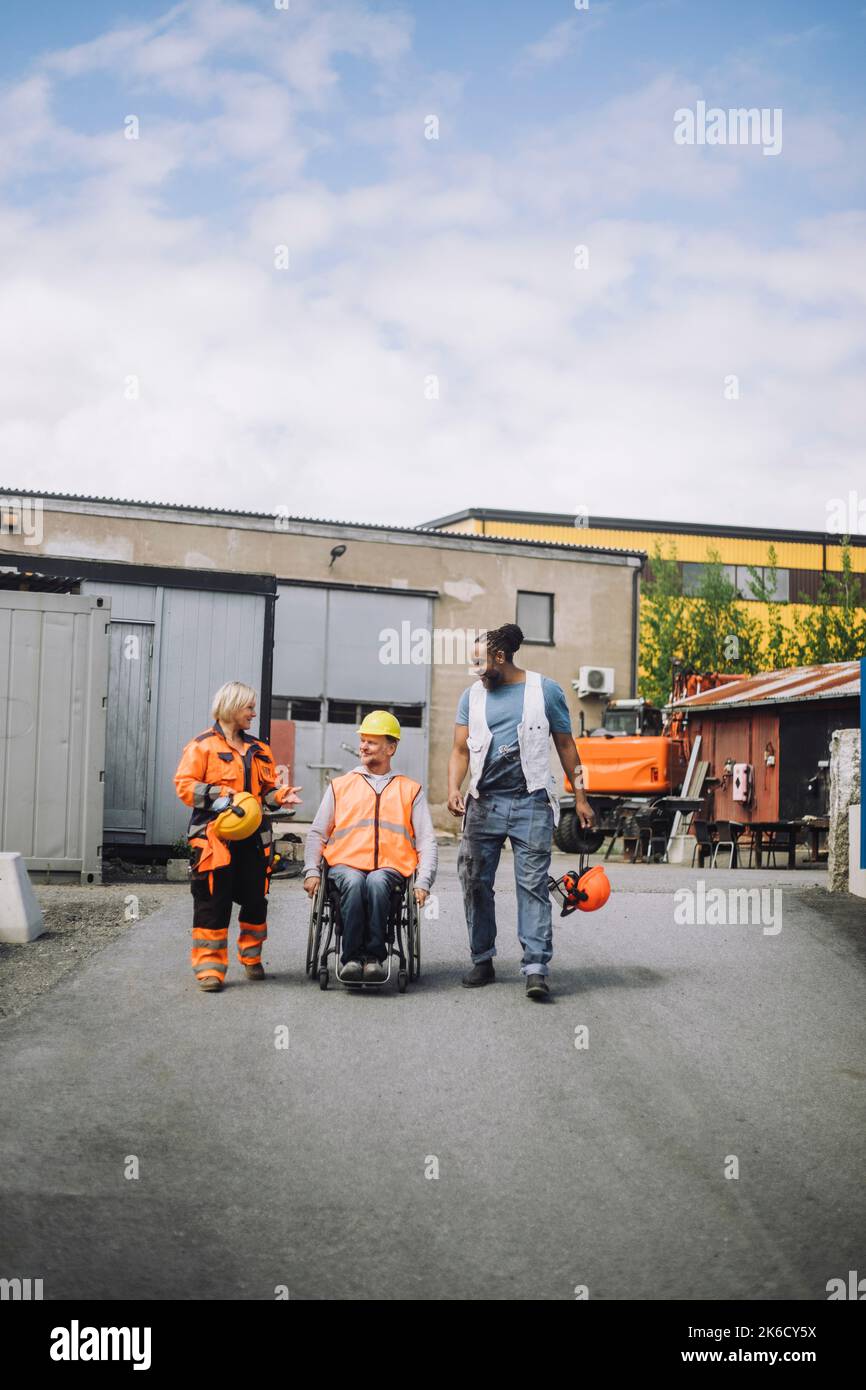 Full length of male and female construction worker talking with ...