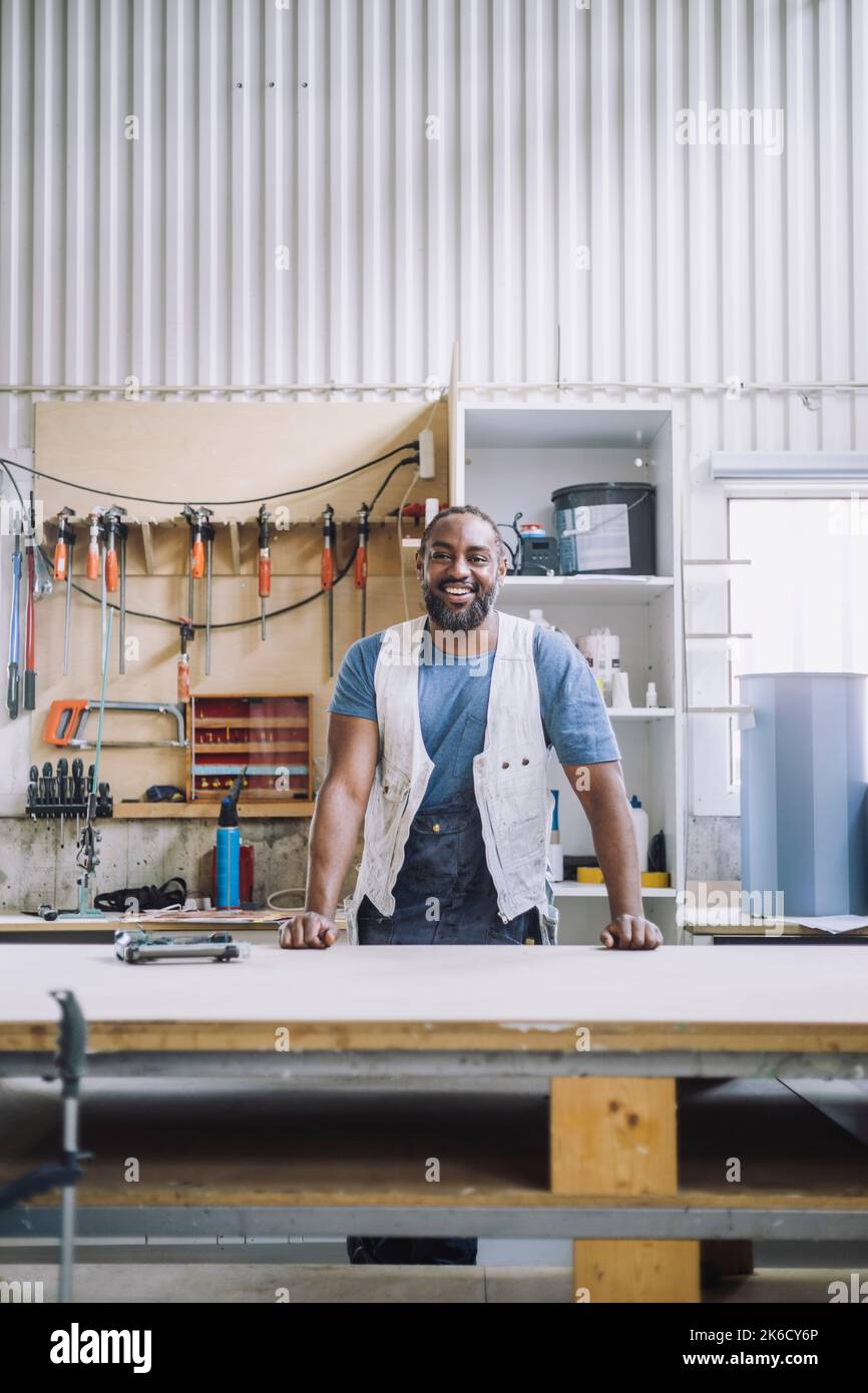Portrait of smiling carpenter standing at workbench Stock Photo - Alamy