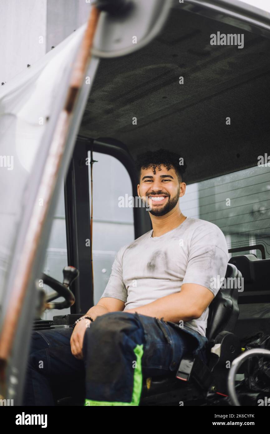 Happy young construction worker sitting in vehicle Stock Photo - Alamy