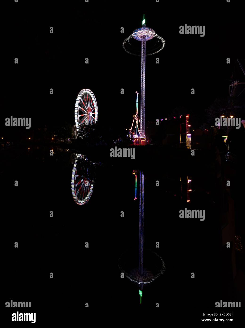 A vertical shot of illuminated Kermis attractions in the dark and their ...