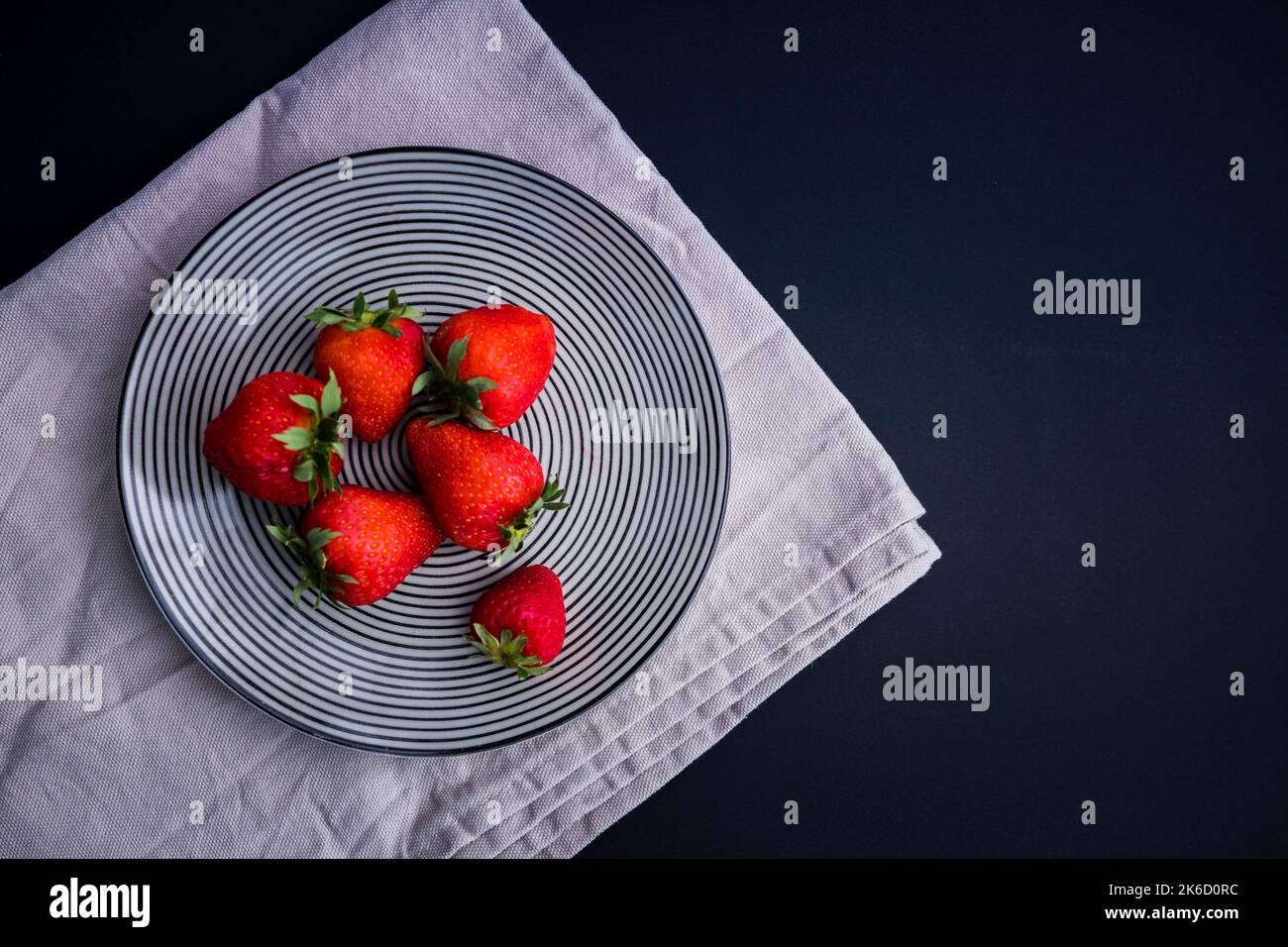 A top view shot of strawberries on a plate isolated on a blue ...