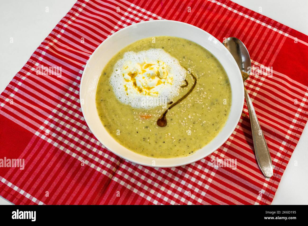 Broccoli soup with sesame seed, black cumin oil and cream on red ...