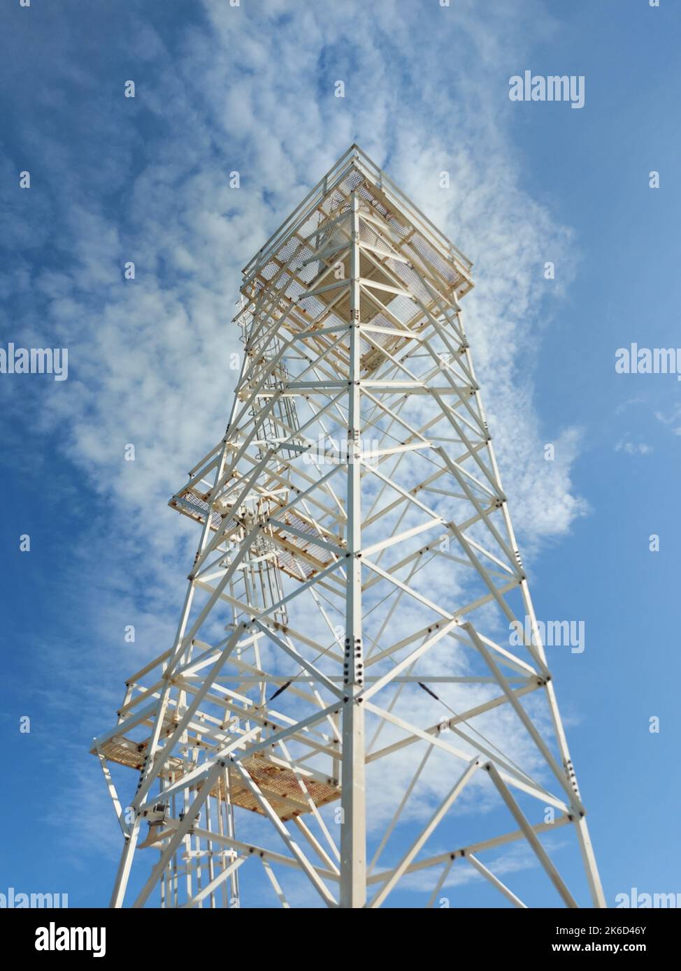 A low angle shot of a steel tower with a cloudy blue sky background ...