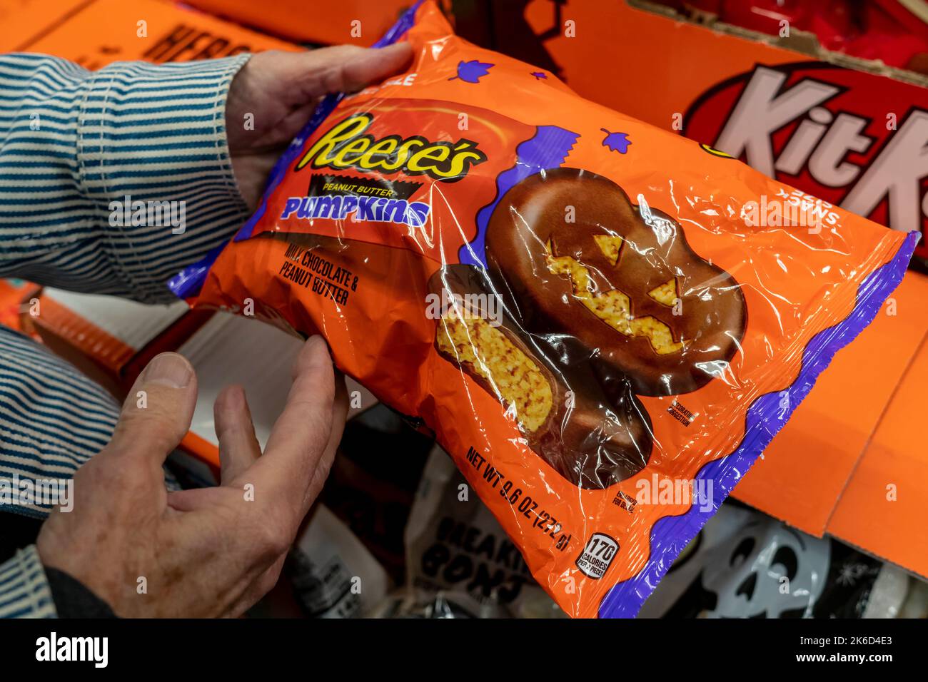 A shopper chooses a bag of Hershey’s Reeses’ Pumpkins Halloween candy ...
