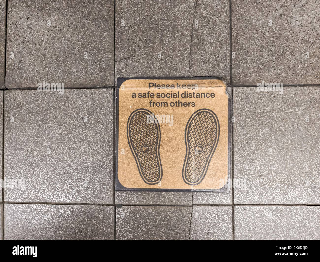 A worn social distancing sticker on the floor of a platform in the ...