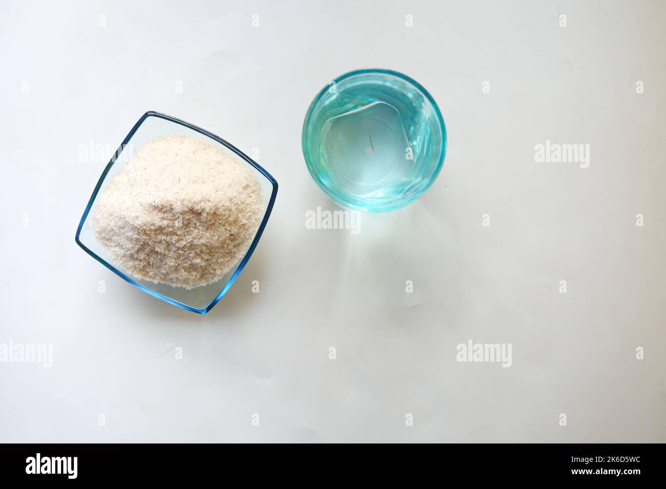 overhead view of Psyllium Seeds and glass of water on white background ...
