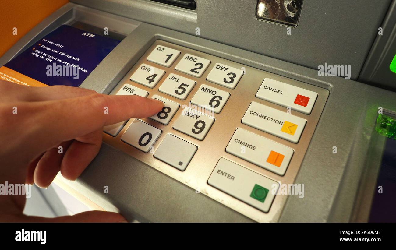 ATM machine and close-up man hand pushing on the pin number button to ...