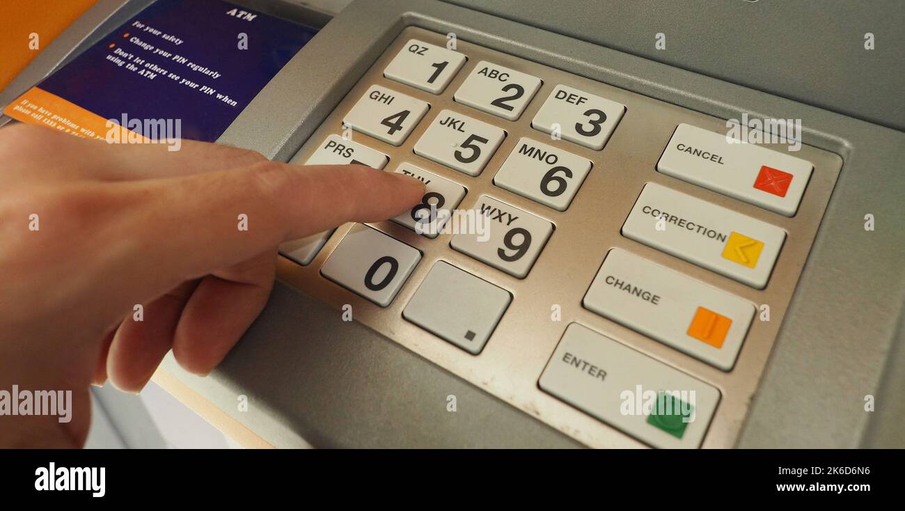 ATM machine and close-up man hand pushing on the pin number button to ...