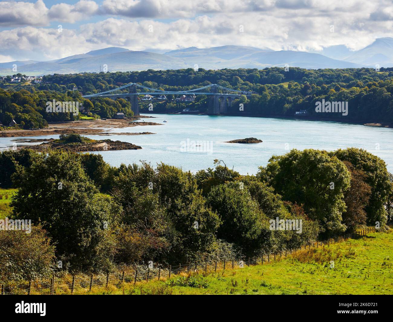 An aerial view of blue water and Menai Strait bridge in rural Wales ...