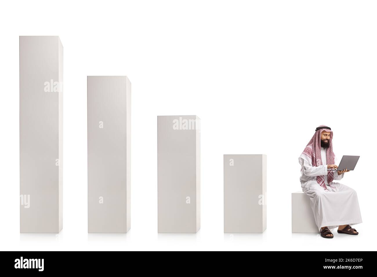 Arab man in ethnic clothes with a laptop computer sitting on a column ...