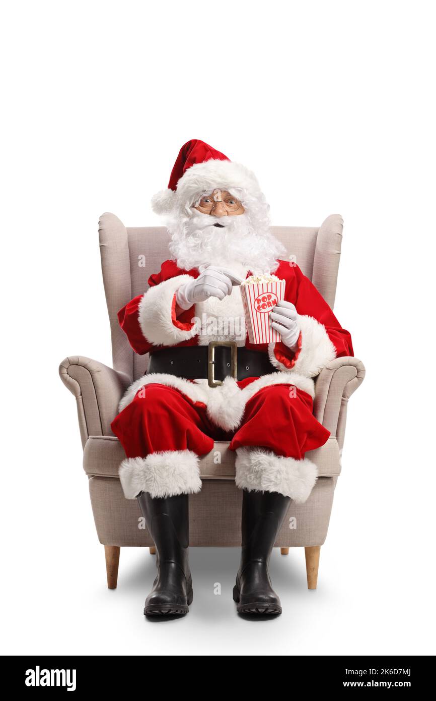 Santa claus sitting in armchair and eating popcorn isolated on white ...