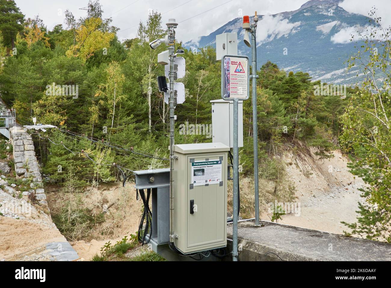A dry river bed surrounded by trees and a foggy mountain with a river ...