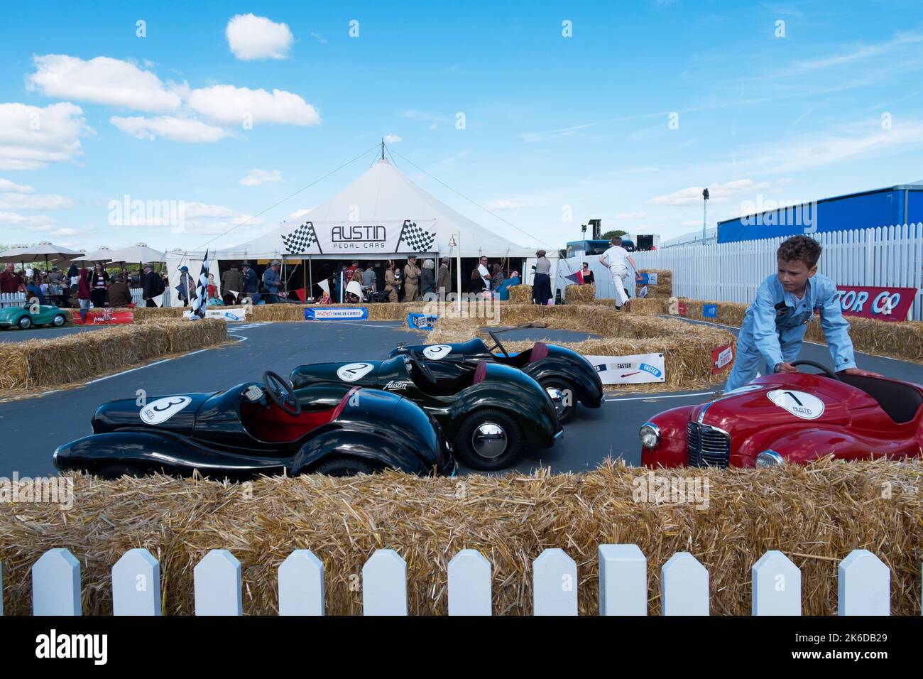 Boy in blue overalls arranging the cars at the small circuit for the ...