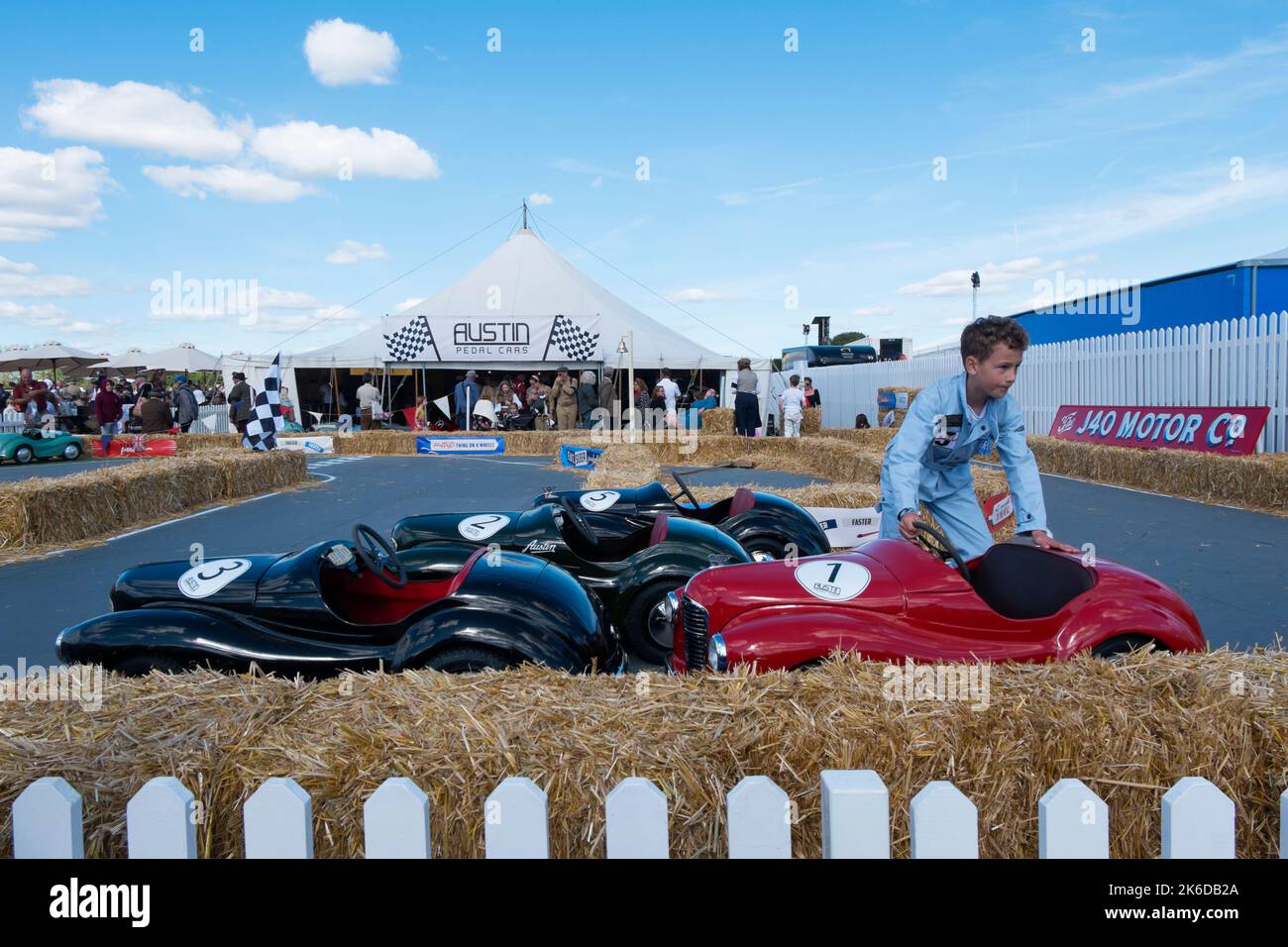 Boy in blue overalls arranging the cars at the small circuit for the ...