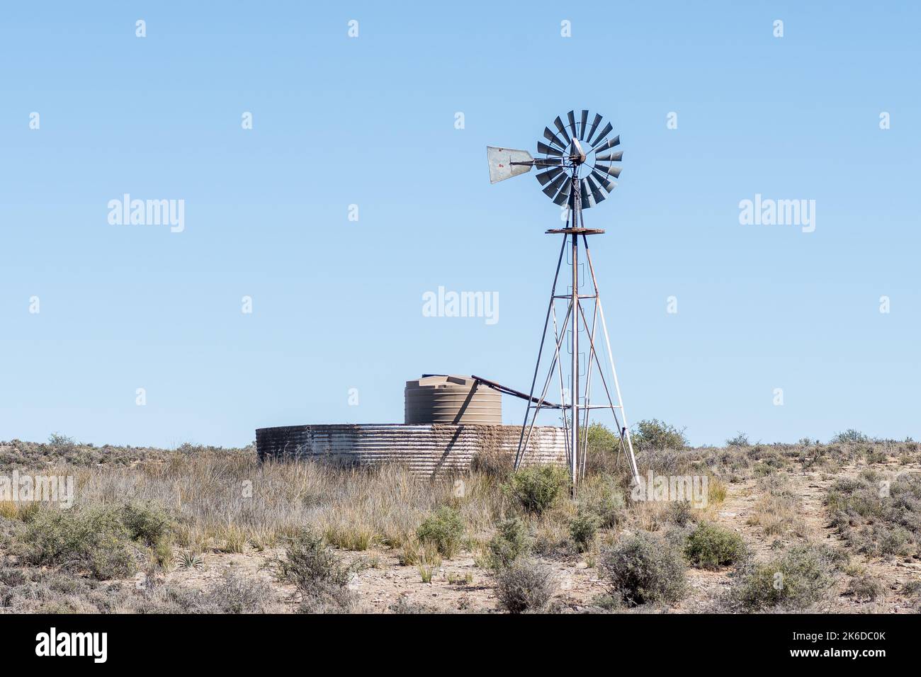 A windmill, with a watertank inside an old corrugated iron dam, on the ...