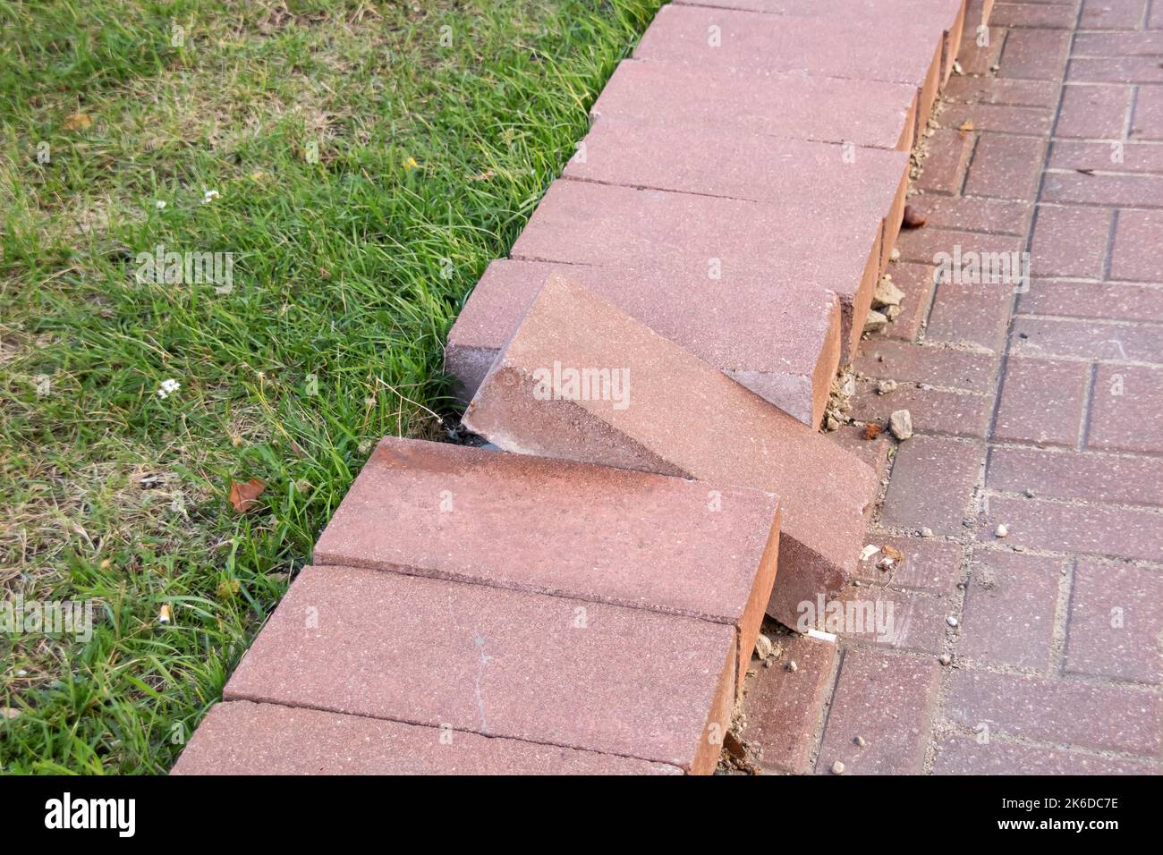 Broken brick sticking out of the sidewalk close up Stock Photo - Alamy