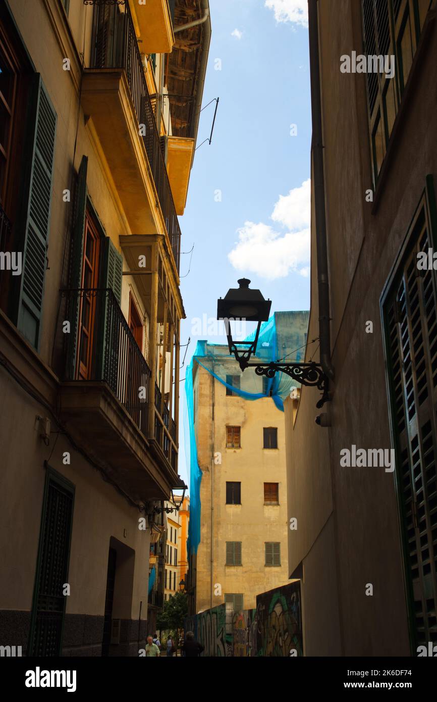 A vertical of people walking in a narrow street in Palma de Mallorca ...