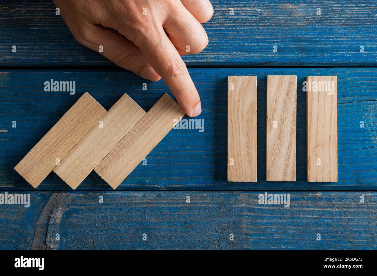 Falling wooden dominos being interrupted by male hand in a conceptual ...