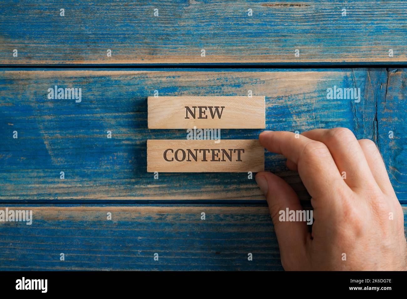 Male hand stacking two wooden blocks with a New content sign on them on ...