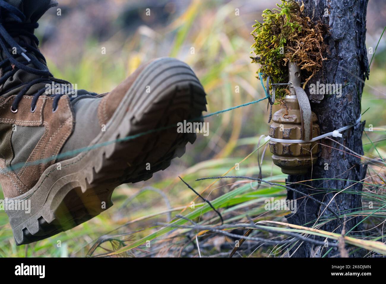 Close-up photo - a soldier steps on a mine trap. The soldier's boot ...