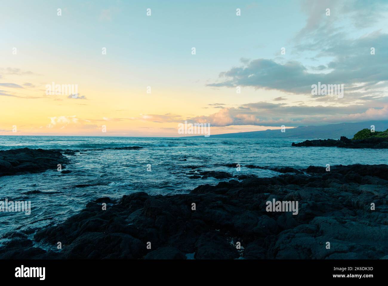A high angle shot of the beautiful rocky seashore of Hawaii at sunset ...