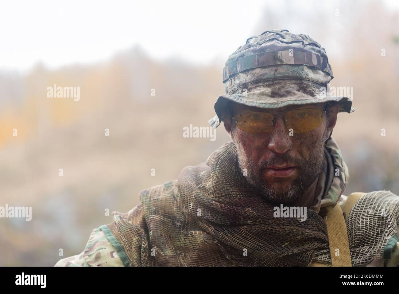 Close-up portrait of a tired soldier with a dirty face. He looking at ...