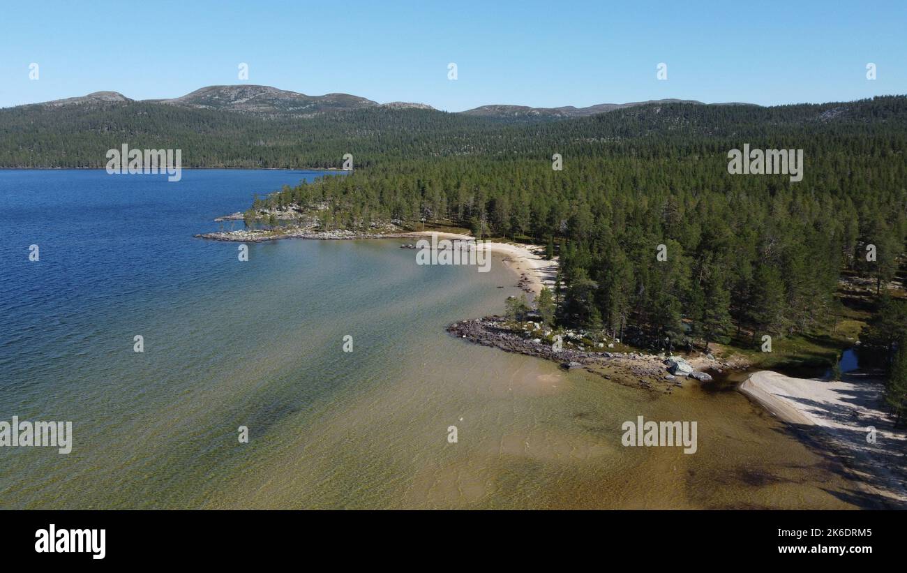 An aerial drone shot of Femunden Lake, Norway, with a forest on the ...