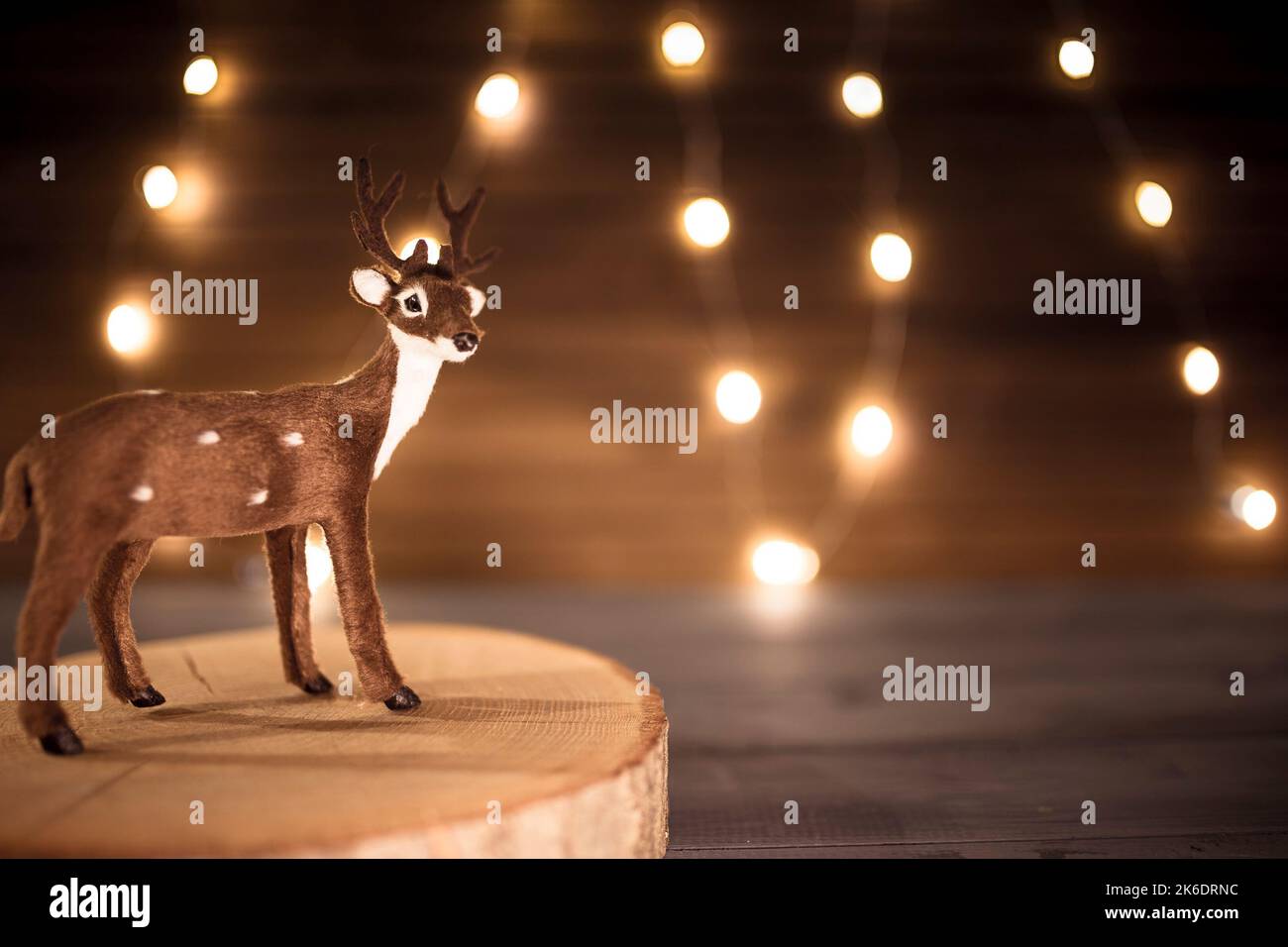 Miniature reindeer on wooden tray, with glowing string lights in the ...