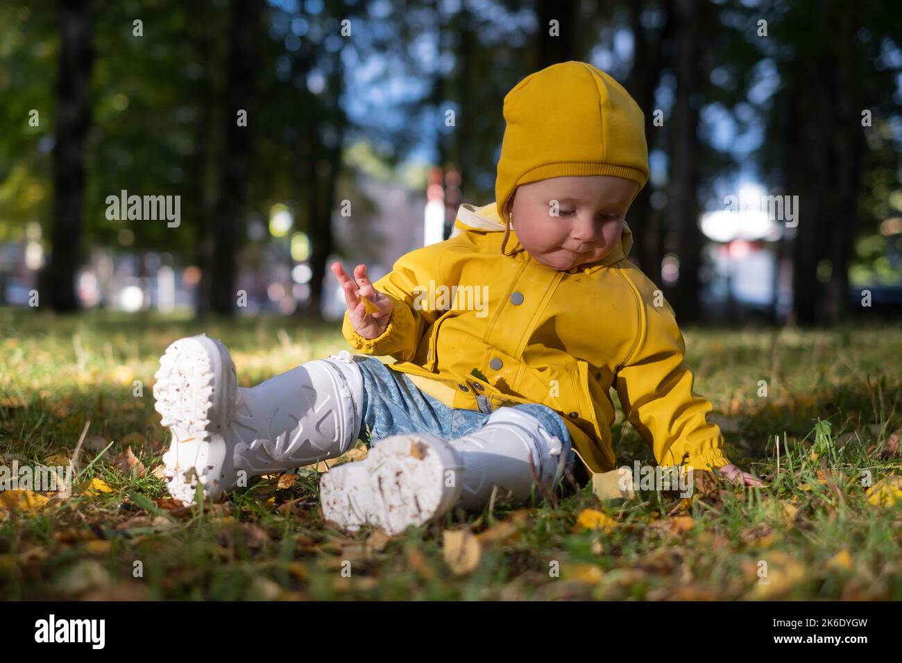 girl in yellow jacket and white rubber boots is running over a puddle ...