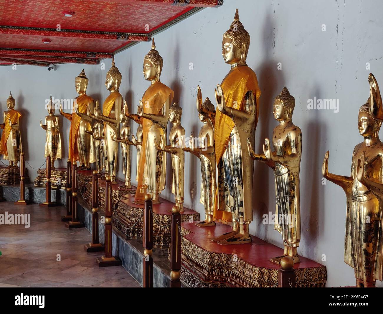 a shot of standing golden buddha statues inside of a temple Stock Photo ...