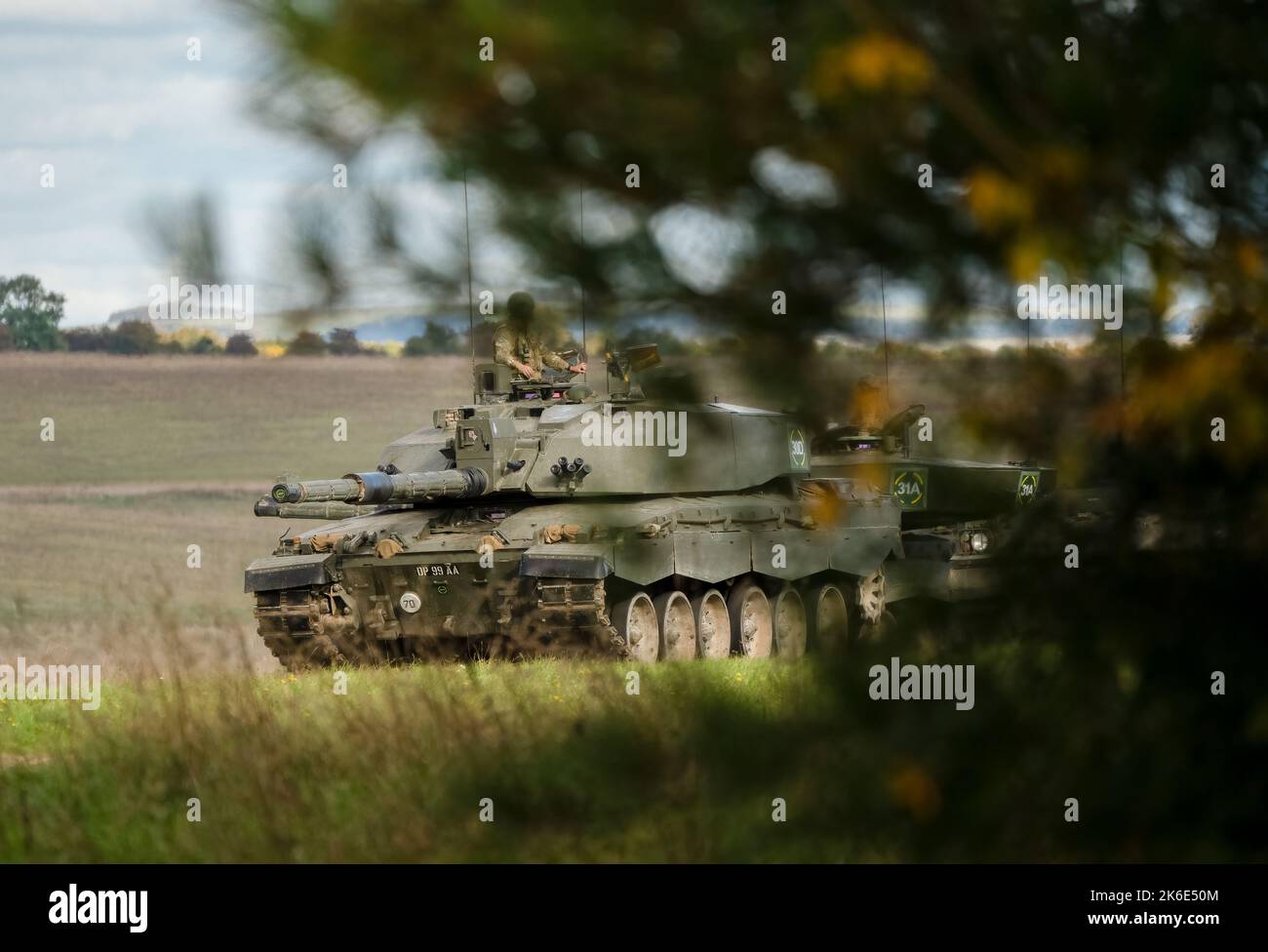British army Challenger II 2 FV4034 main battle tank in action crossing open grass fields, on a ...