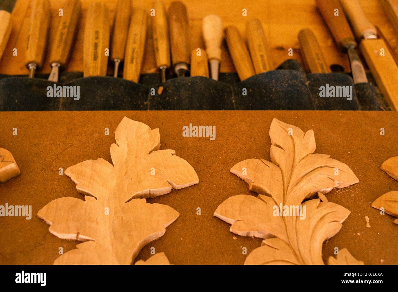 Carved wood scroll work rests on woodworking bench with chisles in view ...