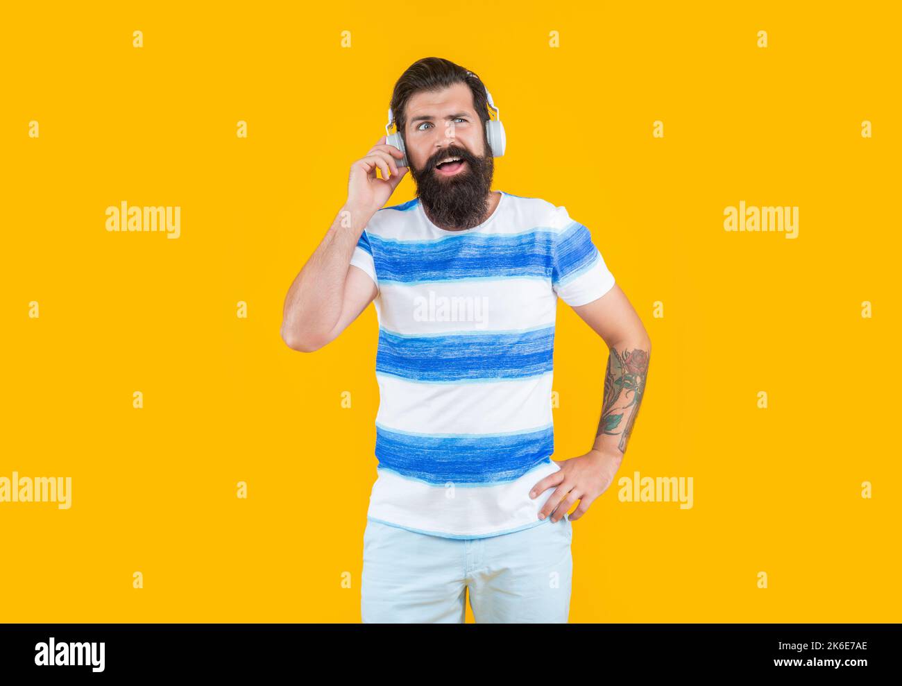 curious hipster man listen music in earphones isolated on yellow ...