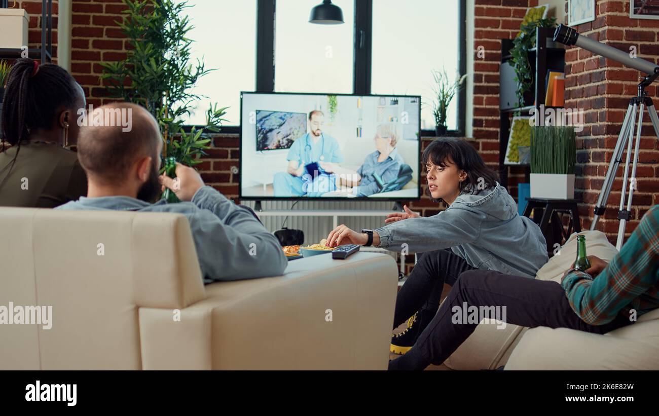 Diverse group of friends looking at action movie on television ...