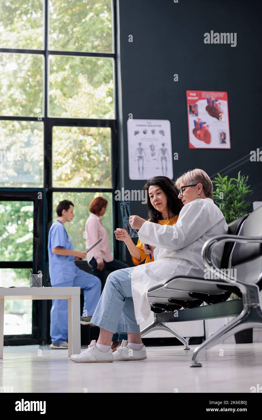 General practitioner and asian patient analyzing x ray scan in medical ...