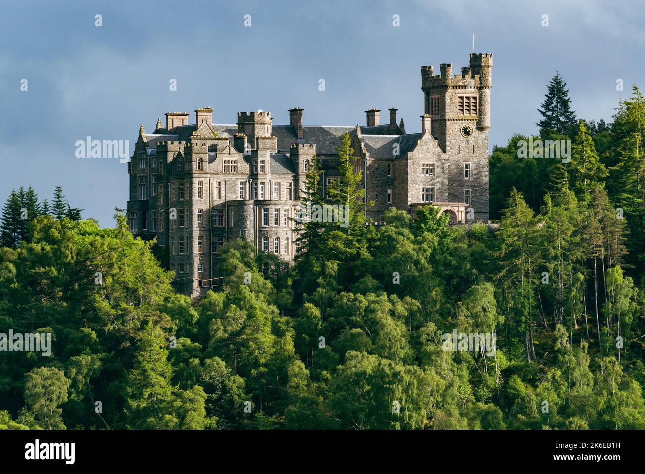 The beautiful exterior of the Carbisdale Castle surrounded by evergreen ...