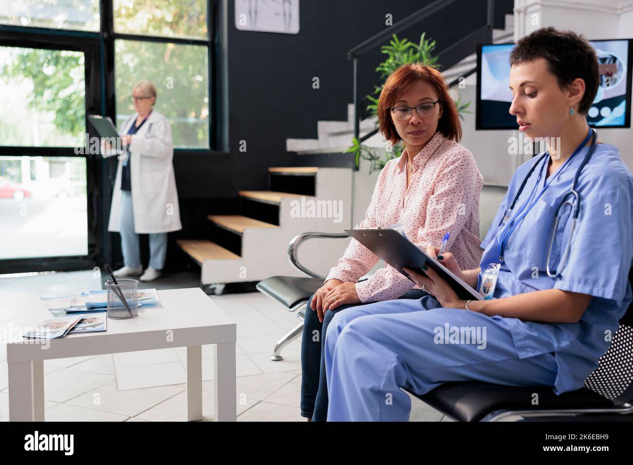 Medical nurse filling in report papers with asian patient, doing ...