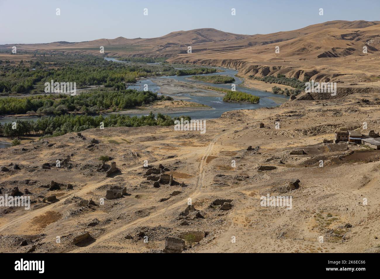 A river flowing on the middle of a dried landscpe under a clear sky ...