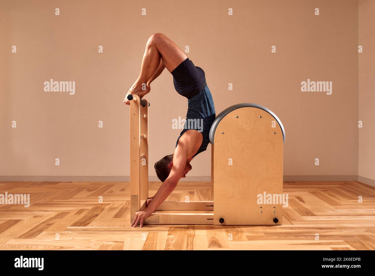 Handsome pilates male instructor performing stretching balance fitness ...