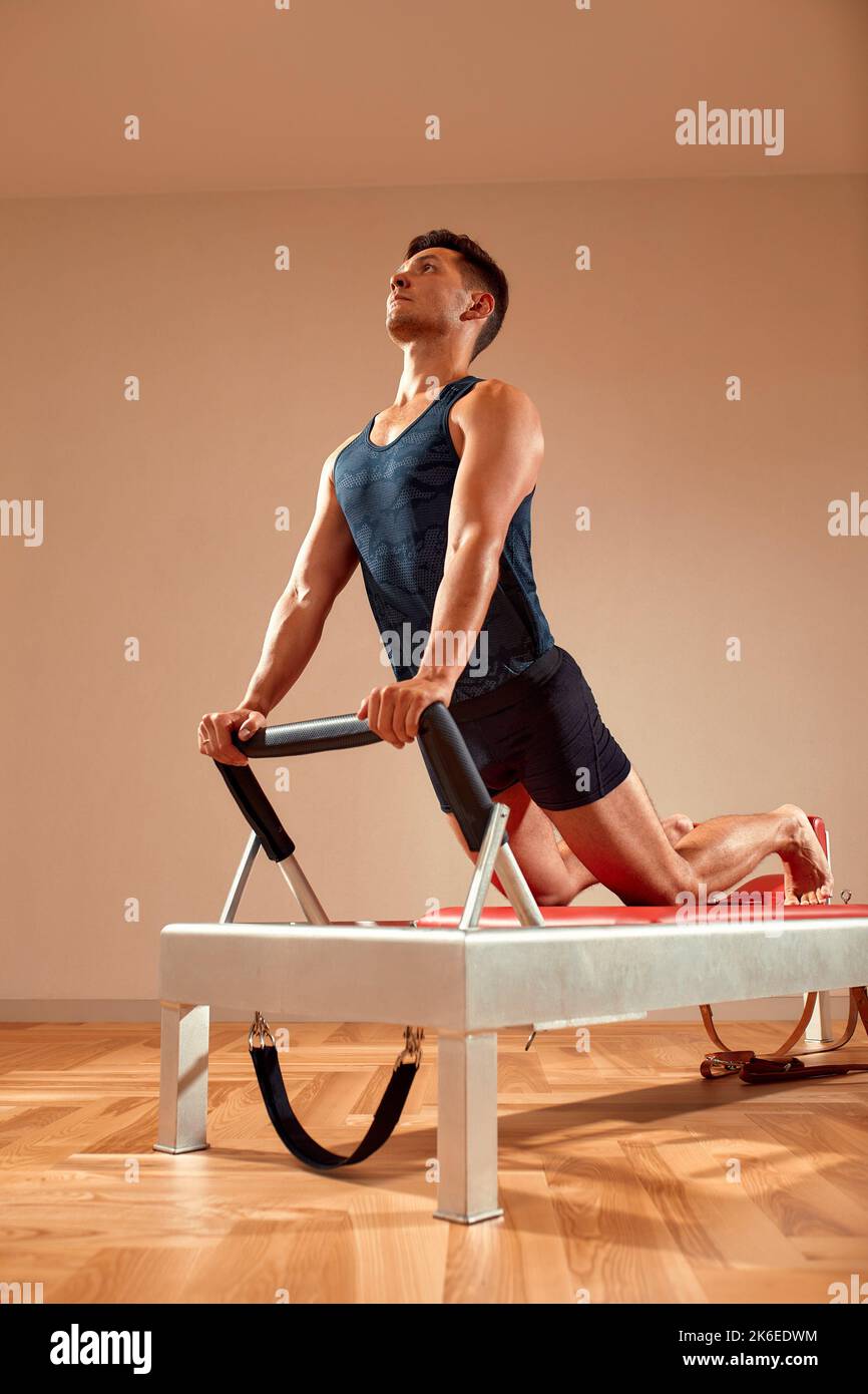 Fit man doing a lunge stretch yoga pilates exercise to strengthen and ...