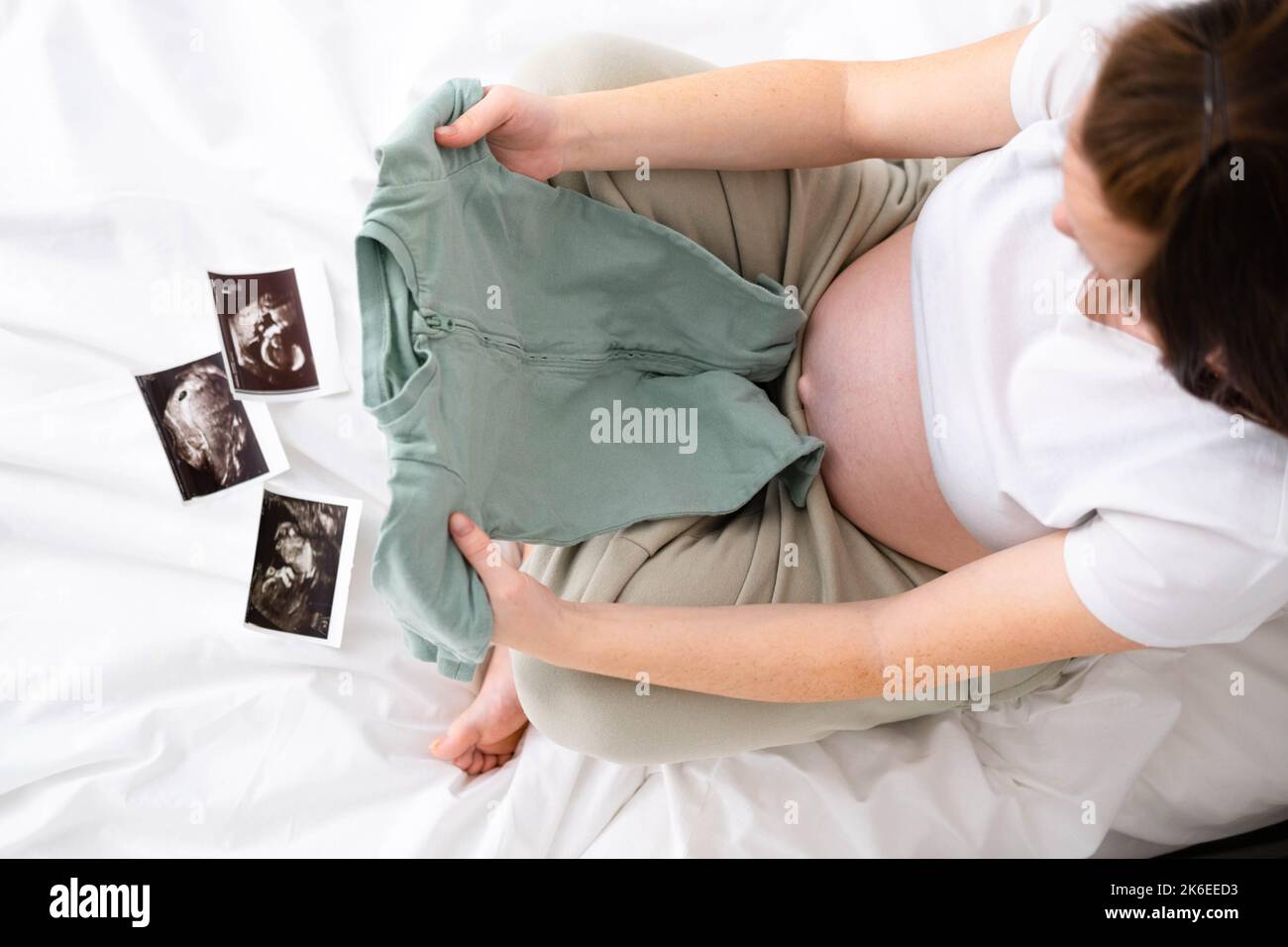 Top view Pregnant mother holding baby clothes in hands, Happy Expectant ...