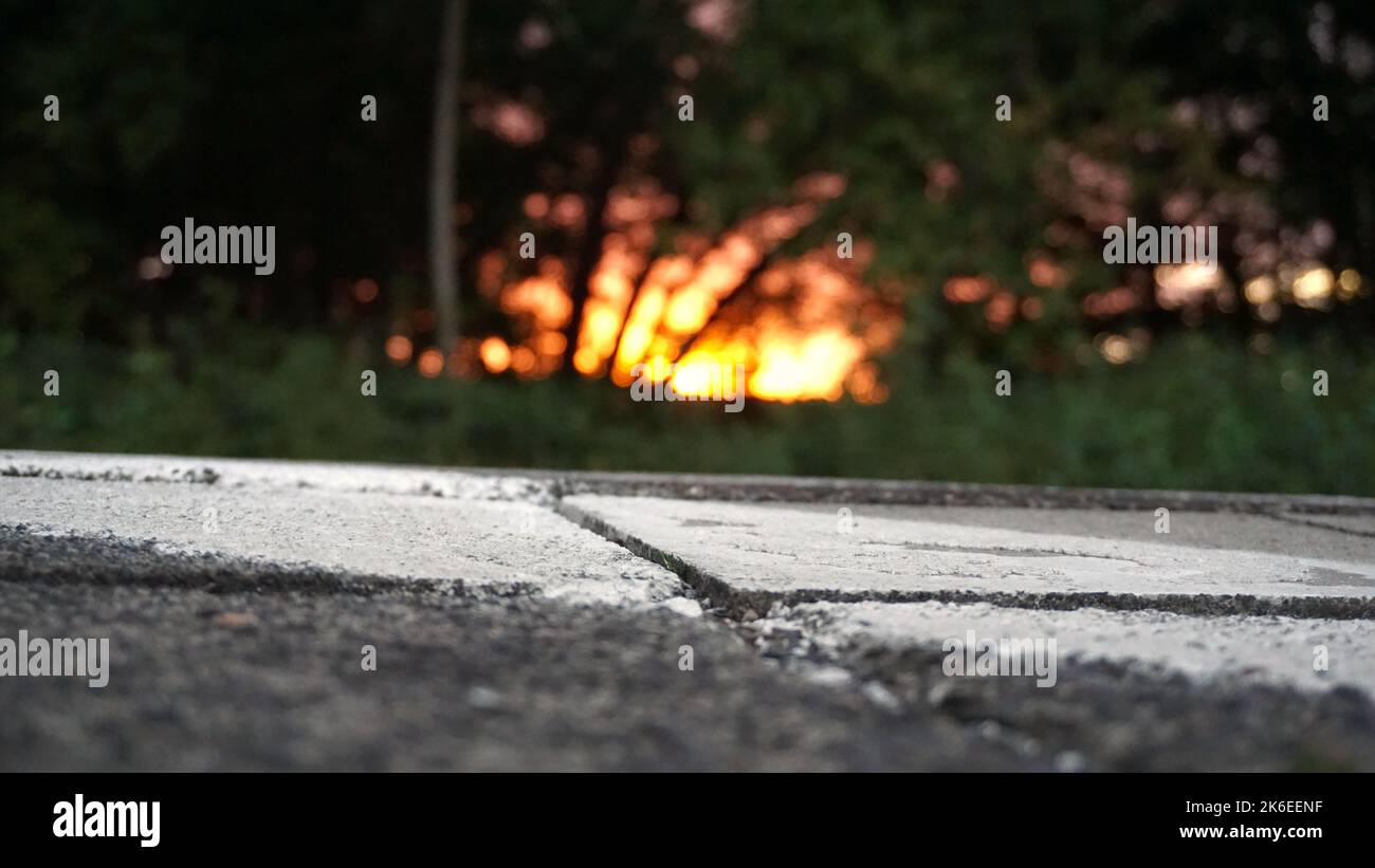 A closeup of a road with blurred trees at sunset in the background ...