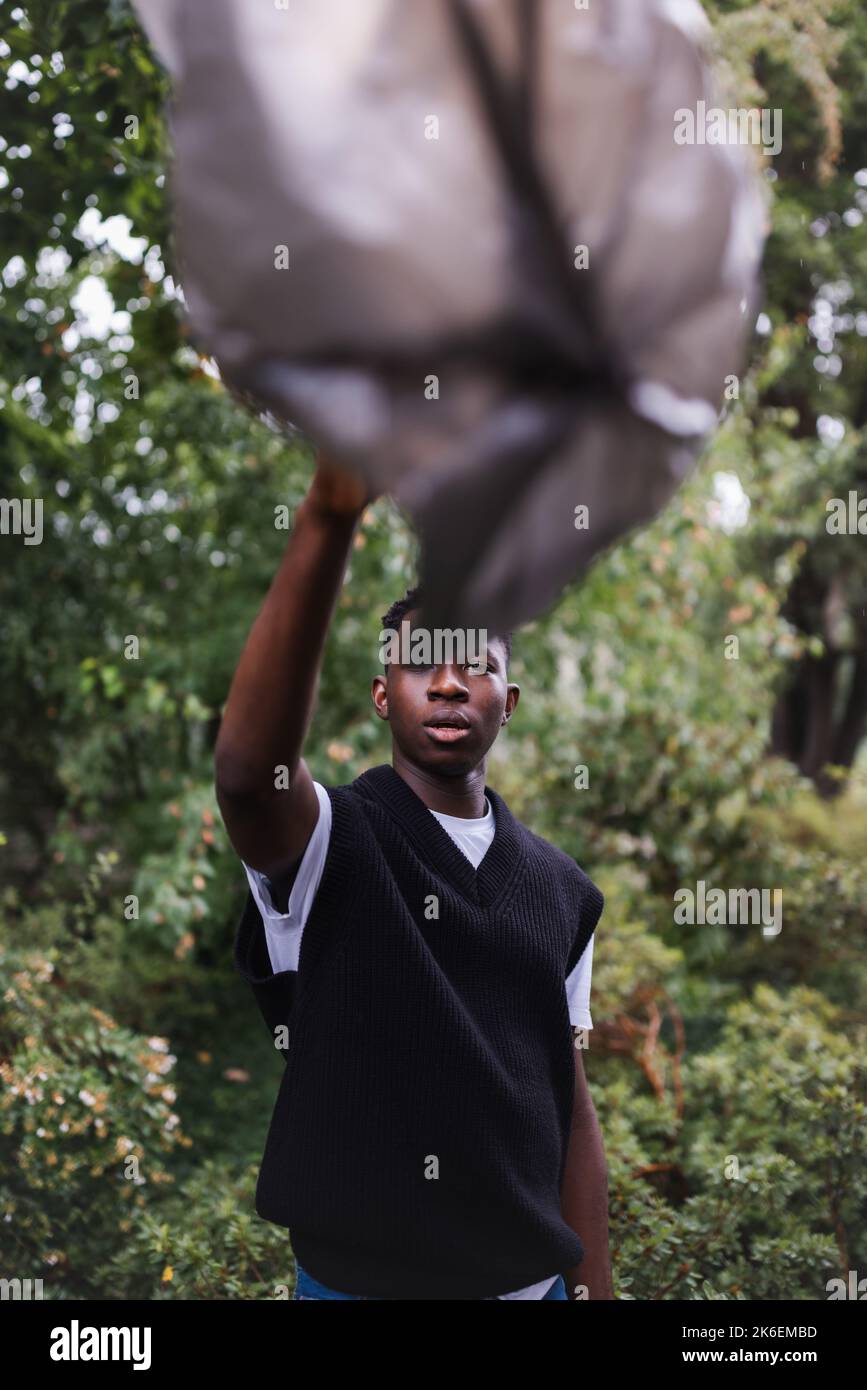 Young African American man outdoor throwing plastic trash bag in the ...