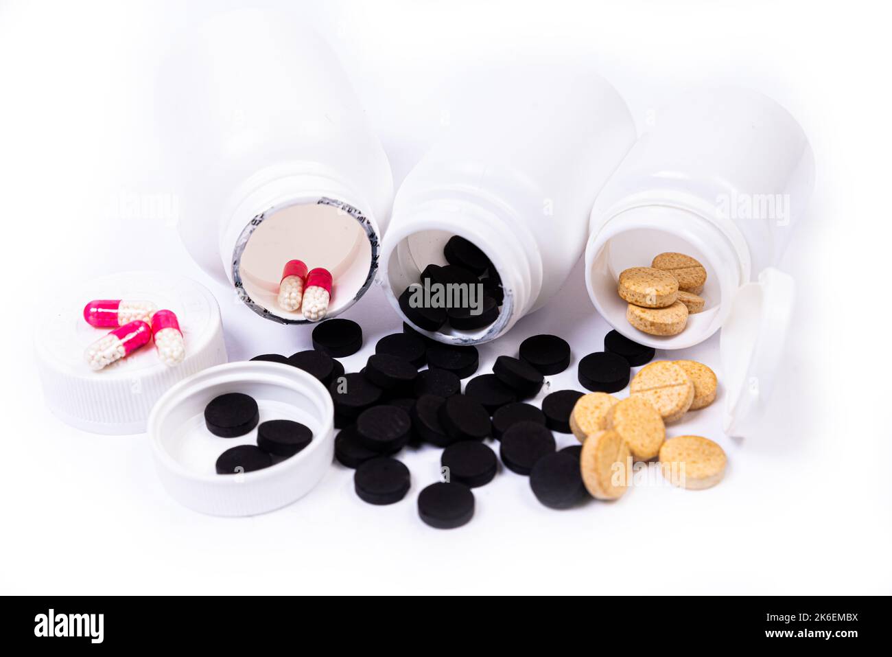 Medical white black orange pills spill out of a white jar on an ...