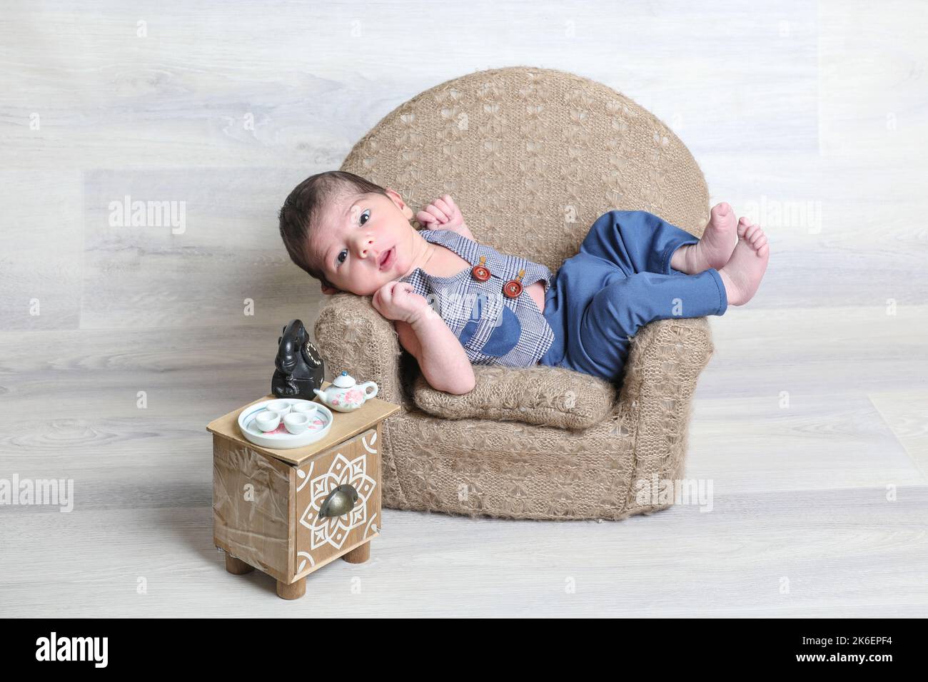 new born baby boy in beautiful dress lying at little chair,tiny stool ...