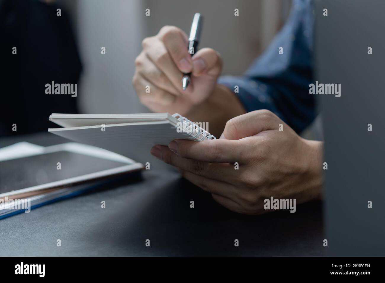 male hand writing in notebook with pen on laptop computer in modern ...